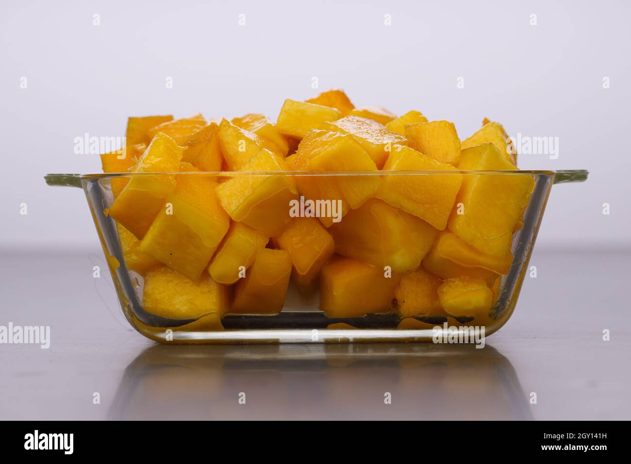 Ripe Mango cubes or cut piece arranged in a glass square container with ...