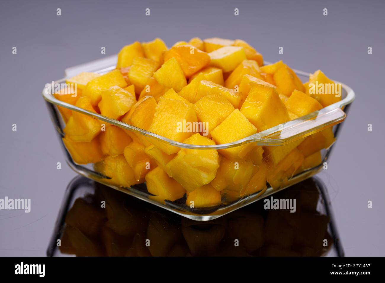 Ripe Mango cubes or cut piece arranged in a glass square container with ...
