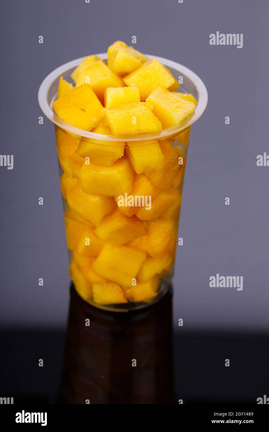 Ripe Mango cubes or cut piece arranged in a transparent glass with ...