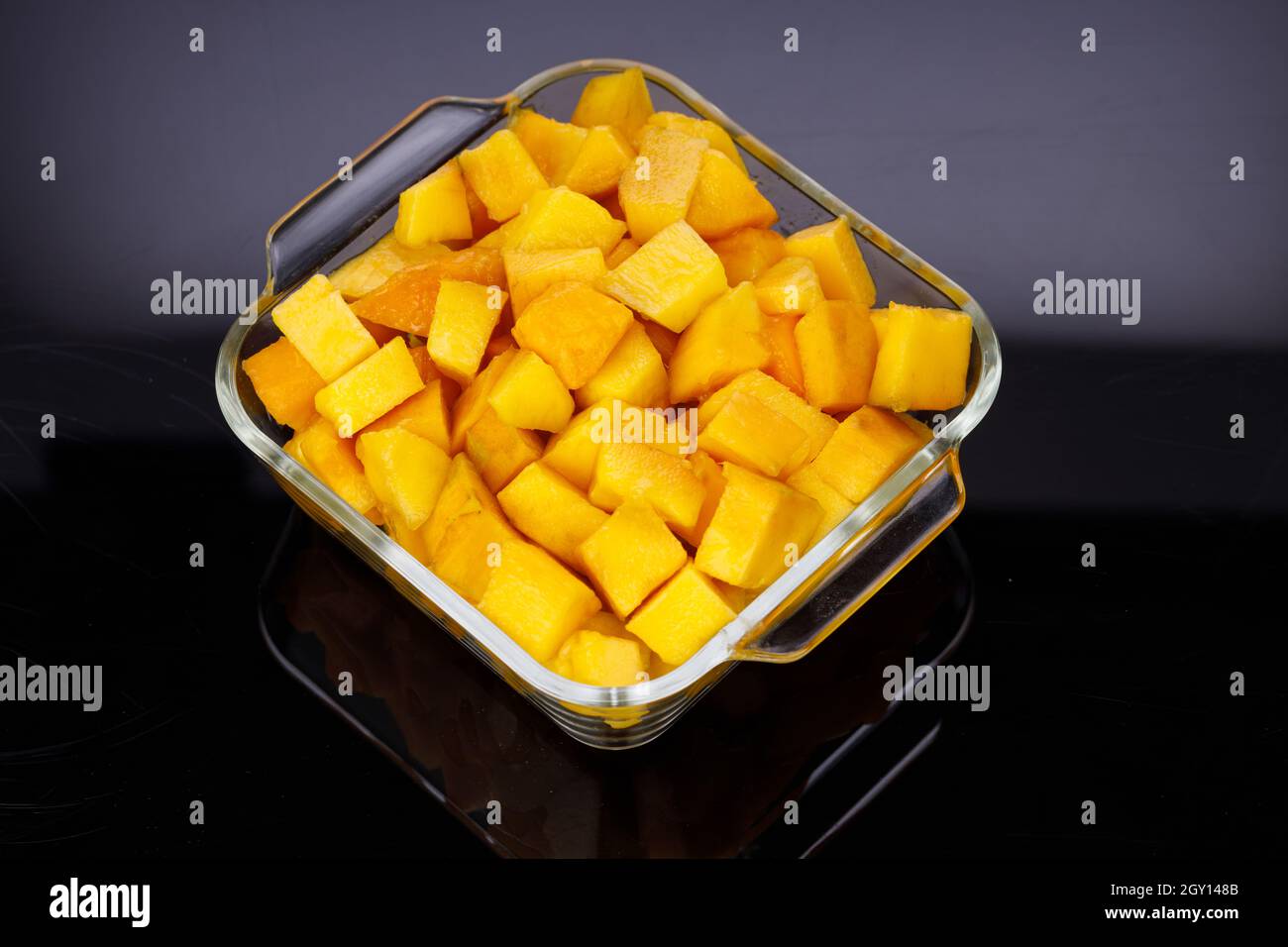 Ripe Mango cubes or cut piece arranged in a glass square container with ...
