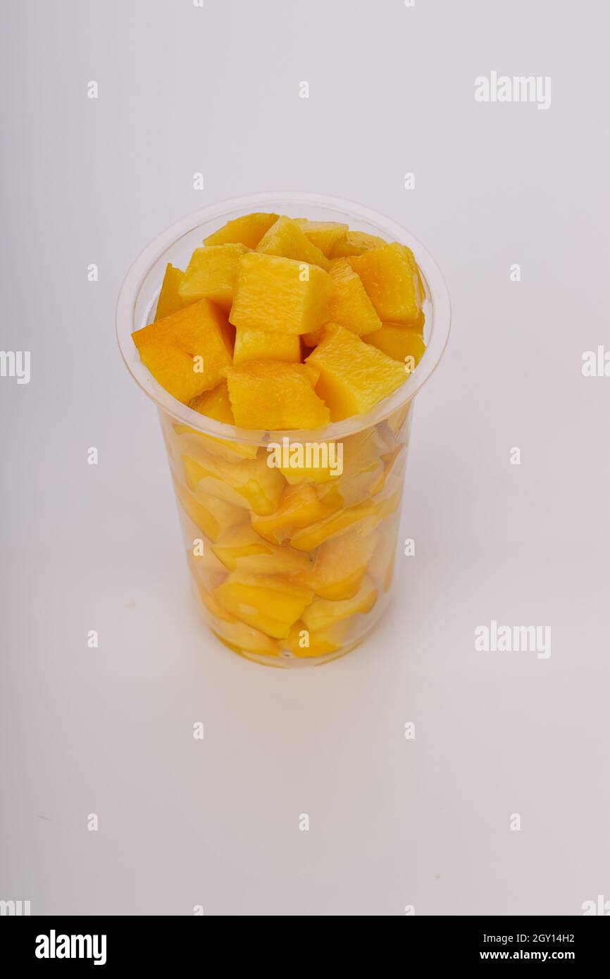Ripe Mango cubes or cut piece arranged in a transparent glass with ...