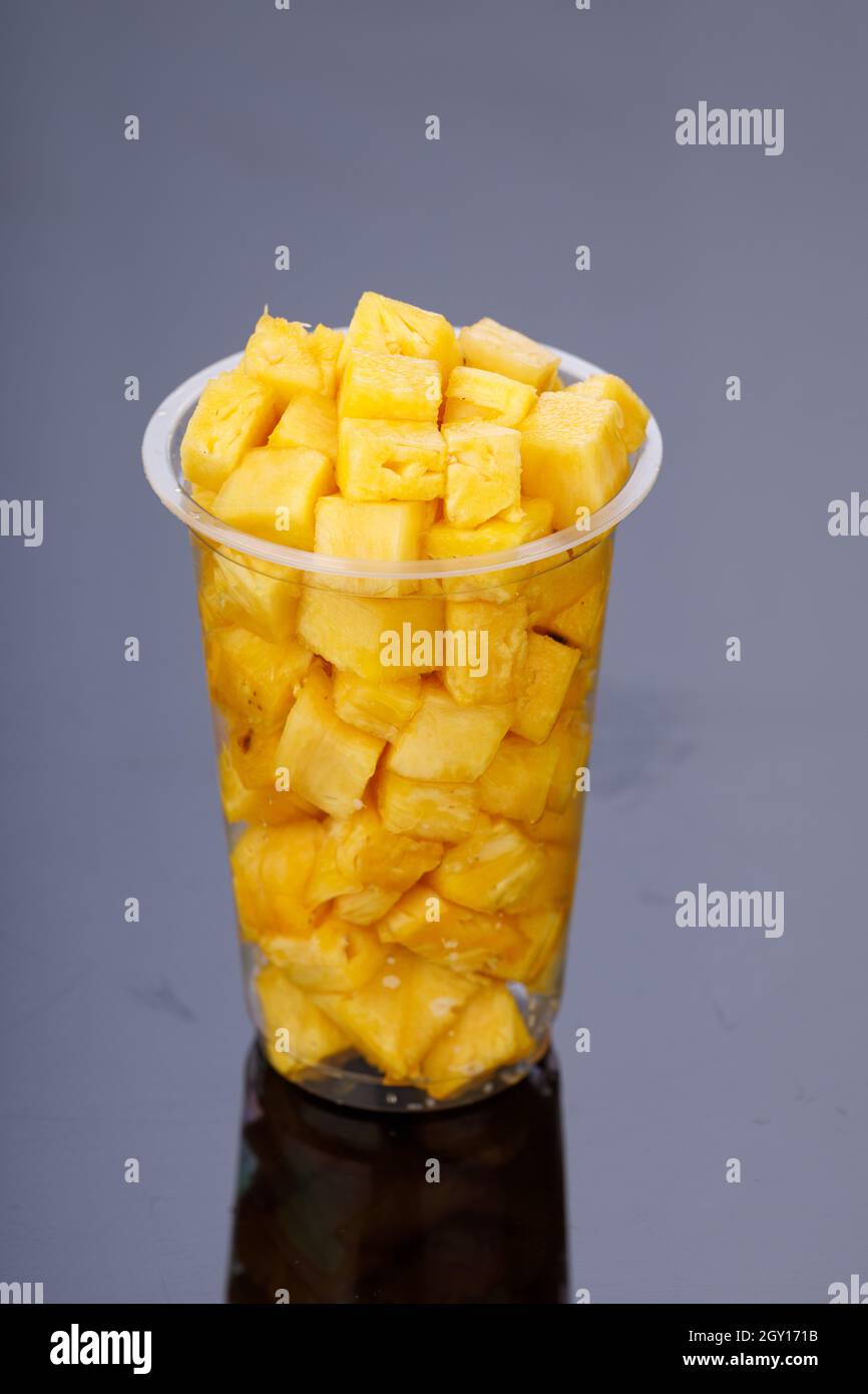 Pineapple cubes arranged in transparent glass with black background ...
