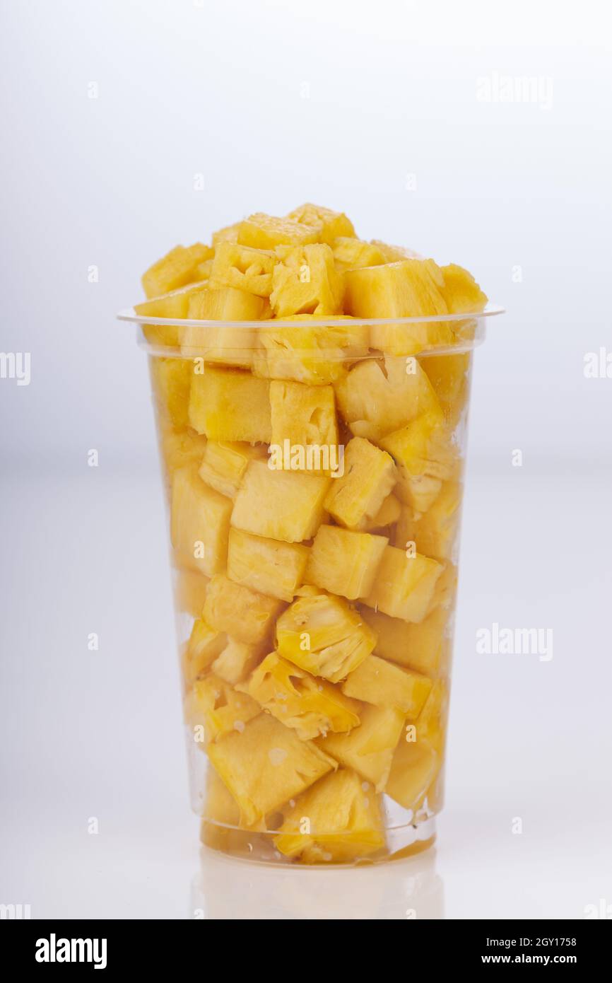 Pineapple cubes arranged in transparent glass with white background ...