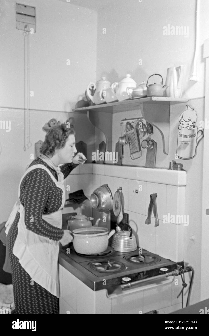 Eine Frau steht am Herd in der Küche und kocht, Deutschland 1930er ...