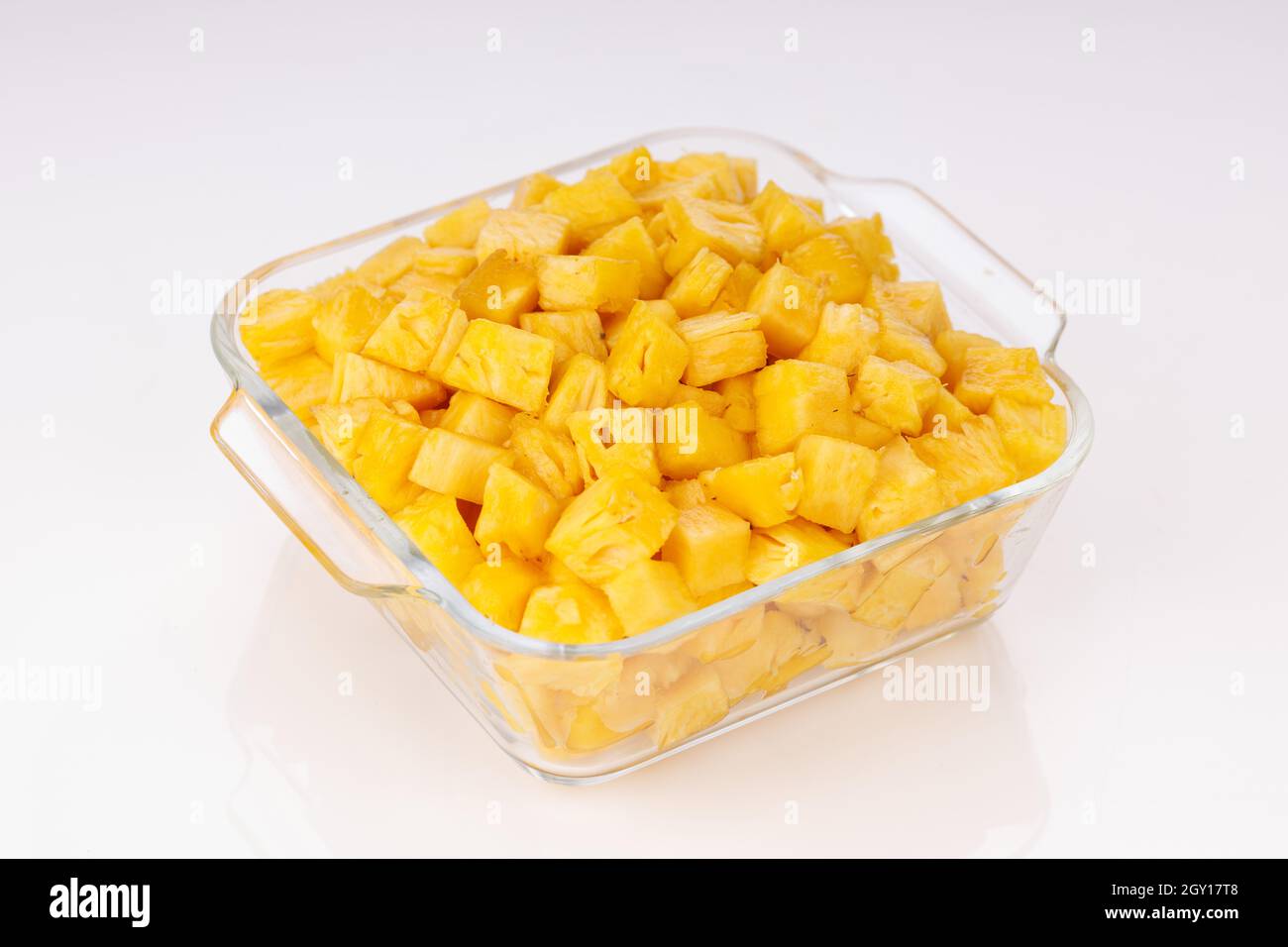 Pineapple cubes arranged in transparent glass container with white ...