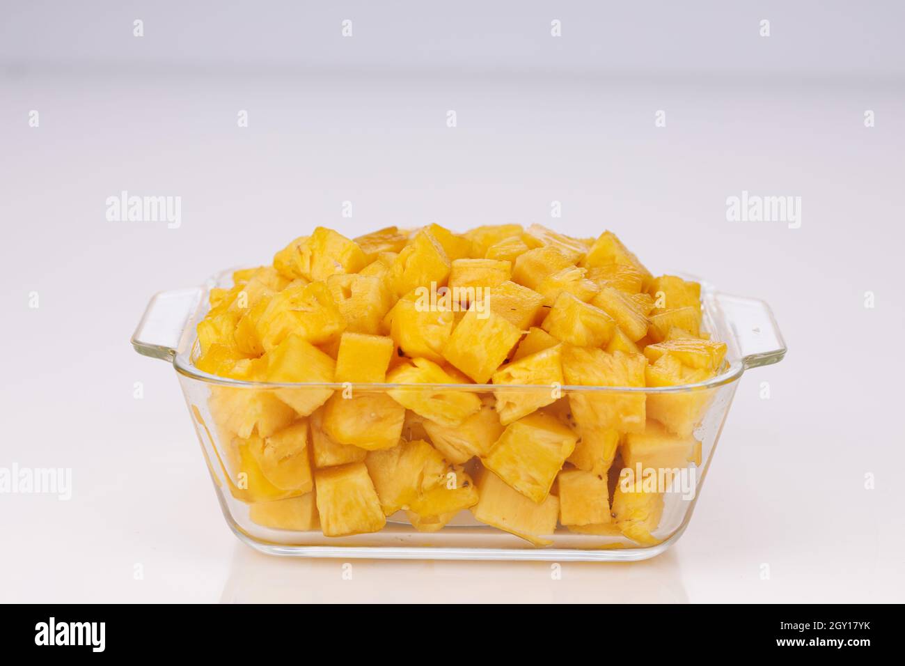 Pineapple cubes arranged in transparent glass square container with ...