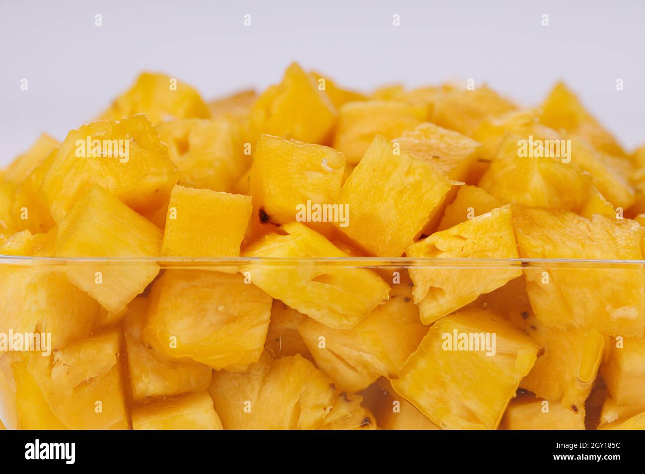 Pineapple cubes arranged in transparent glass square container with ...