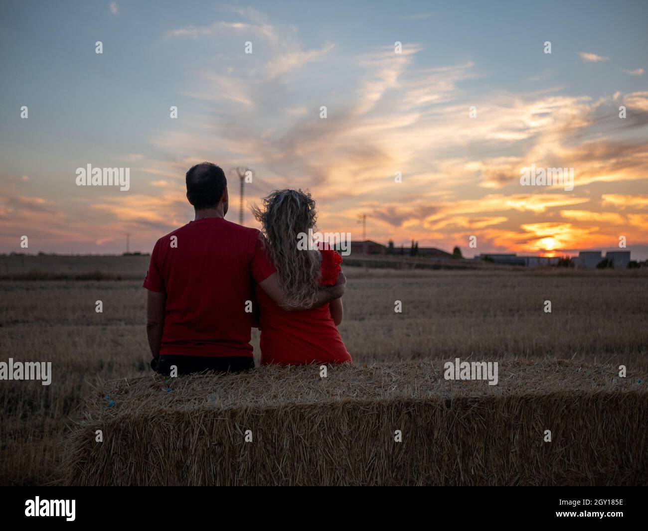 Back view of a romantic young couple looking at the sunset on a beach ...