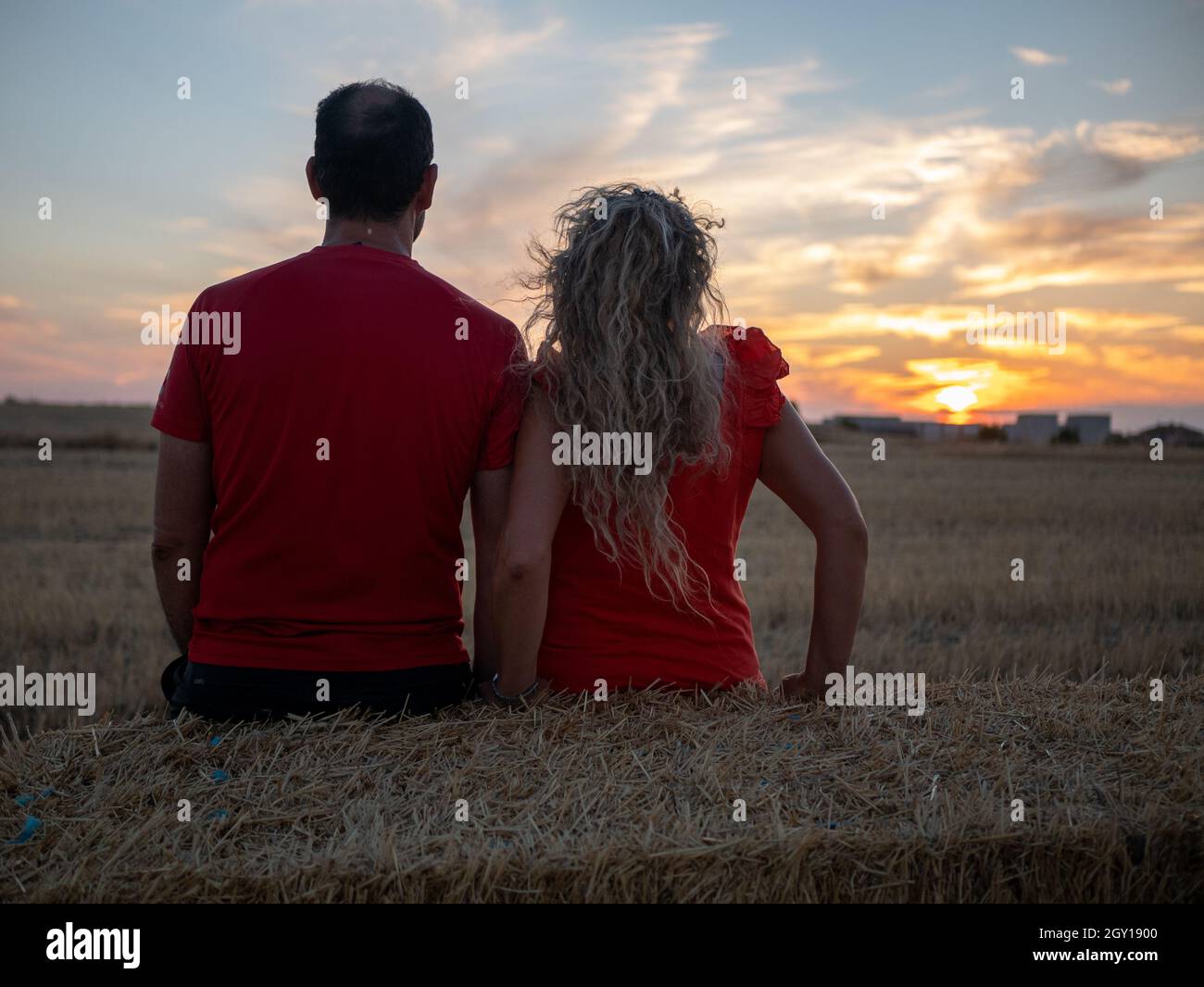 Back view of a romantic young couple in matching shirts looking at the ...