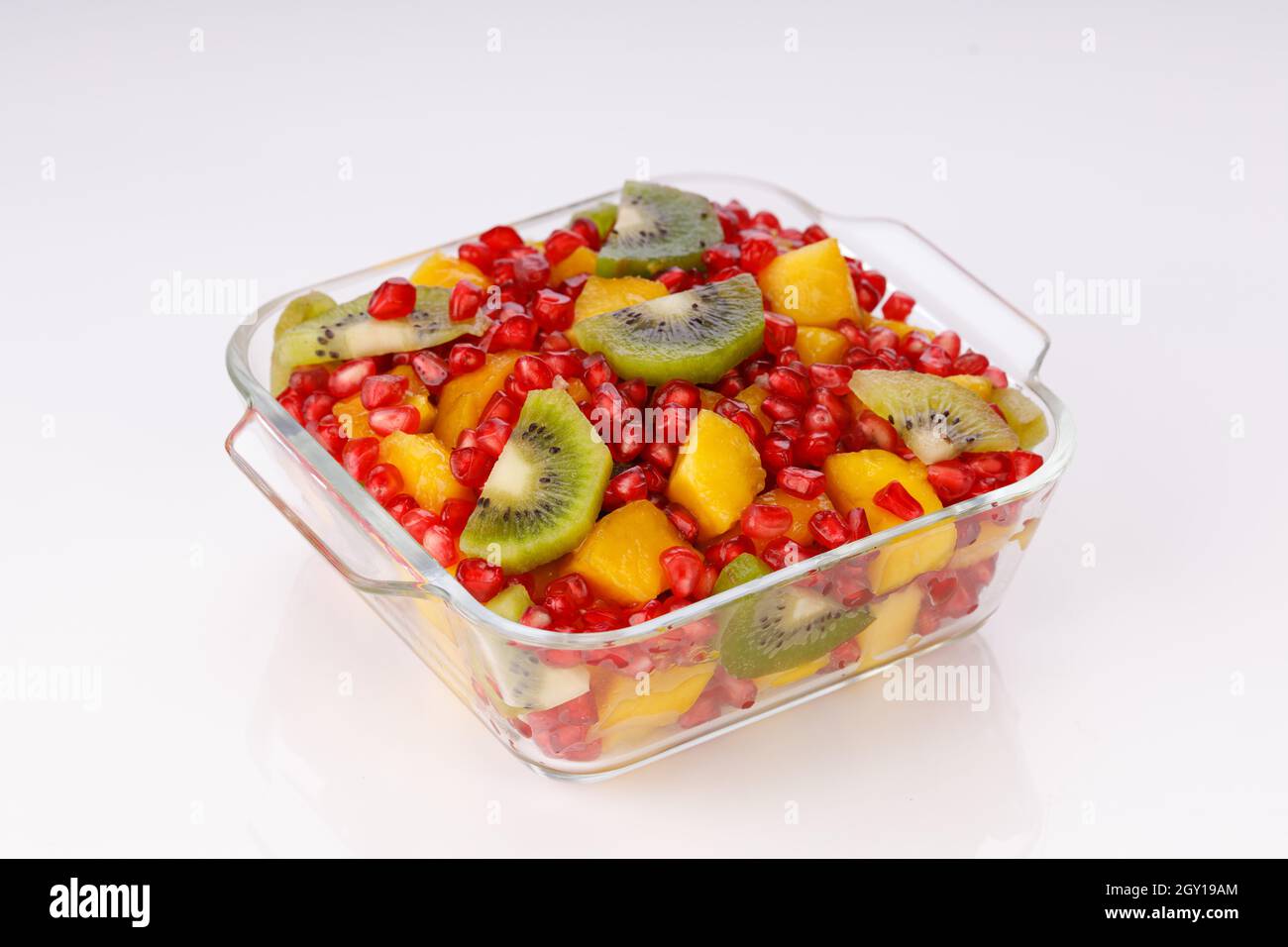 Mixed cut fruits arranged in a transparent glass bowl with white ...
