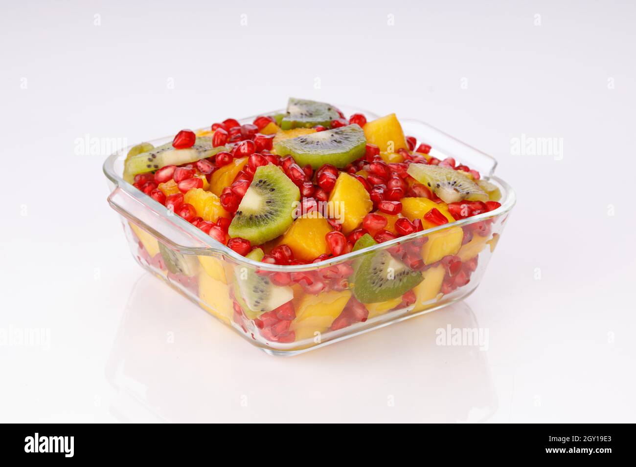 Mixed cut fruits arranged in a transparent glass bowl with white ...