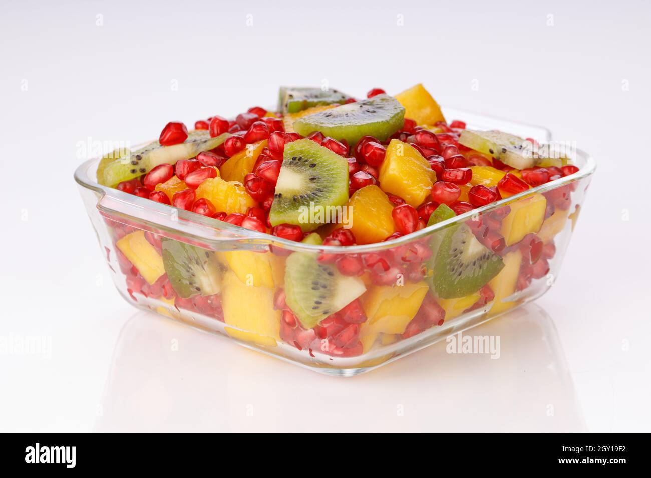 Mixed cut fruits arranged in a transparent glass bowl with white ...