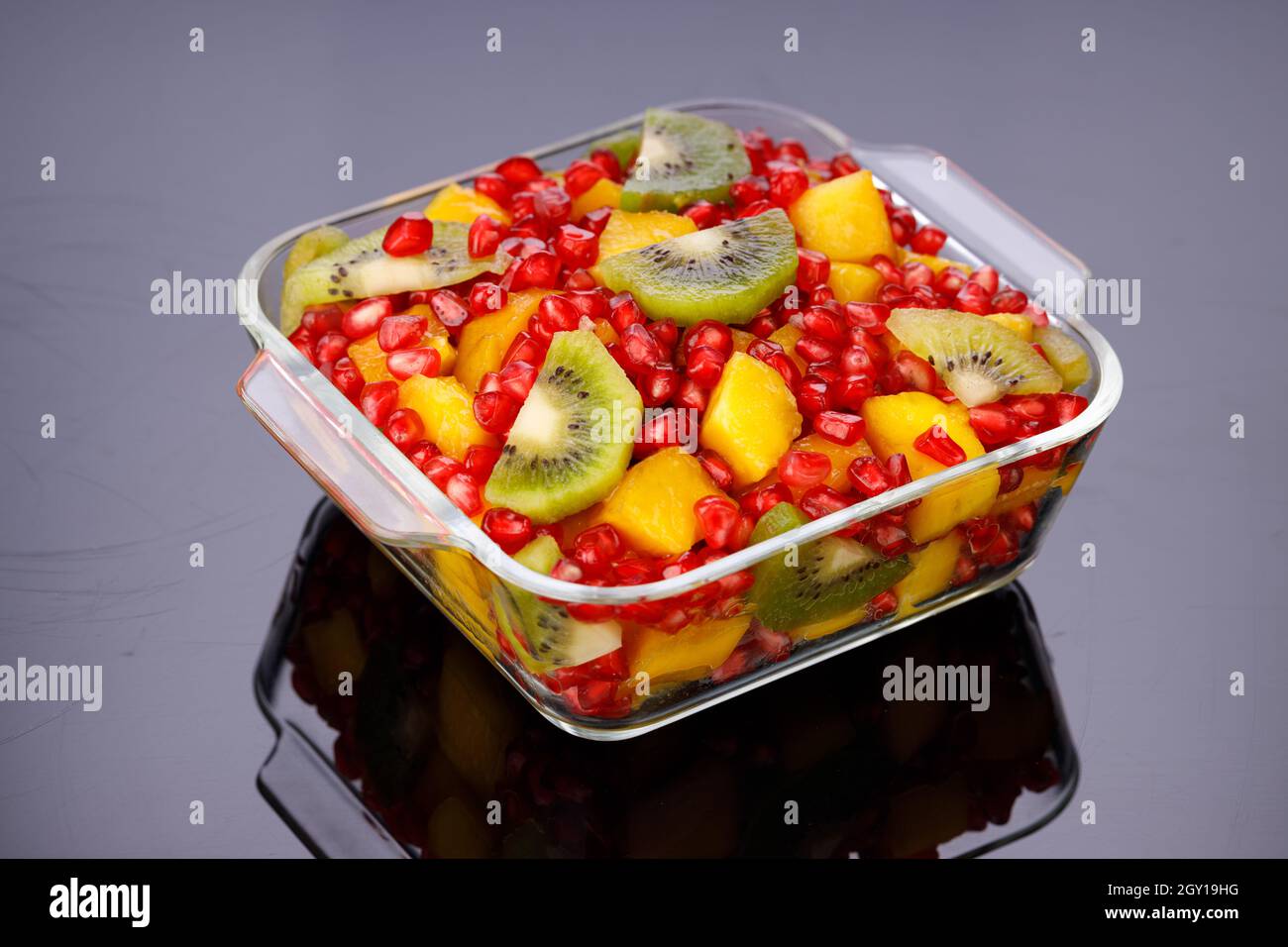 Mixed cut fruits arranged in a transparent glass bowl with black ...