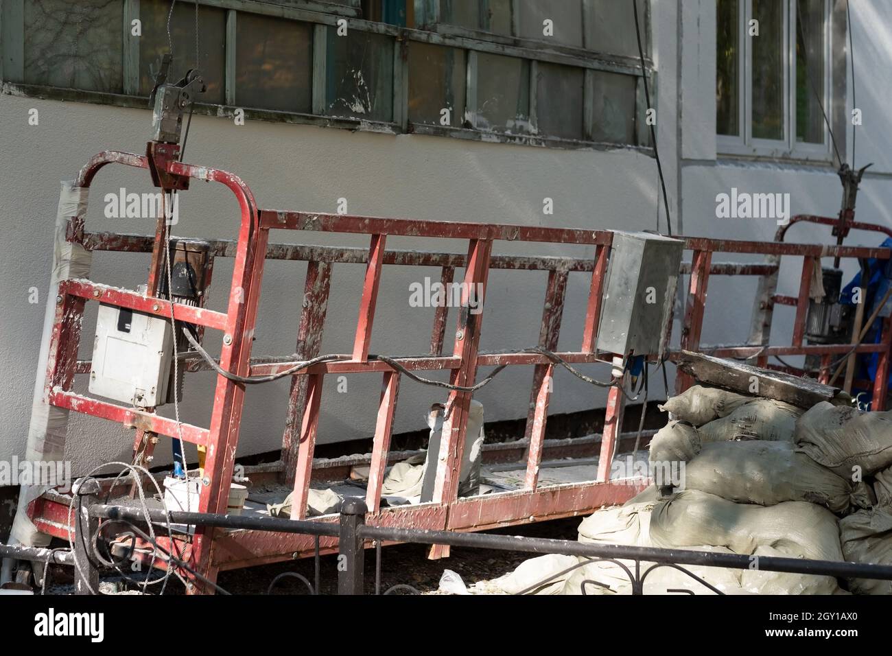 Building with a cradle on ground, preparing for repair of a facade ...