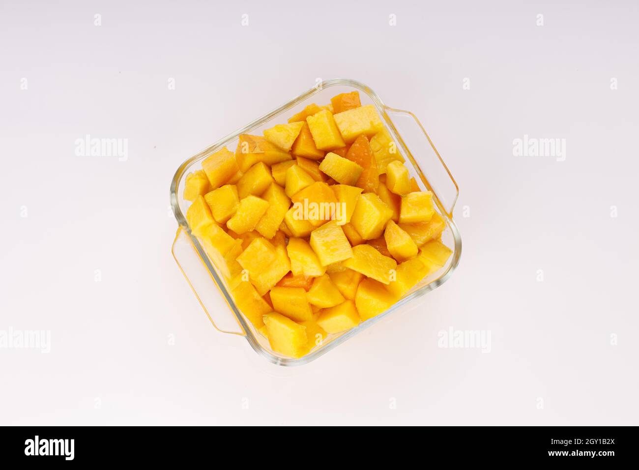 Ripe Mango cubes or cut piece arranged in a glass square container with ...