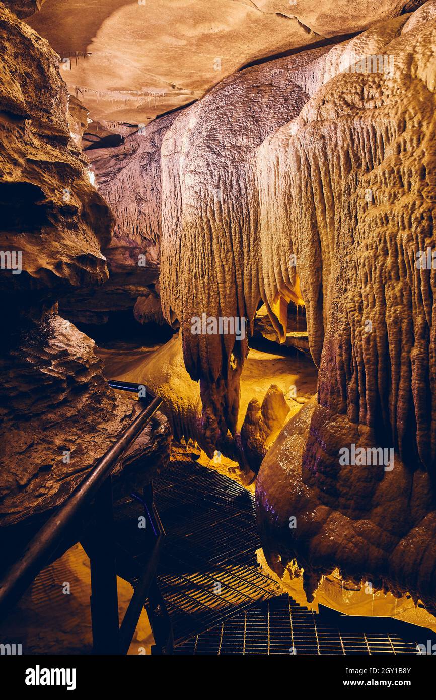 Metal path through underground cave tour with stalagmites and ...