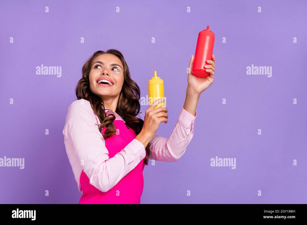 Portrait of attractive cheerful wavy-haired chef maid holding sauces ...