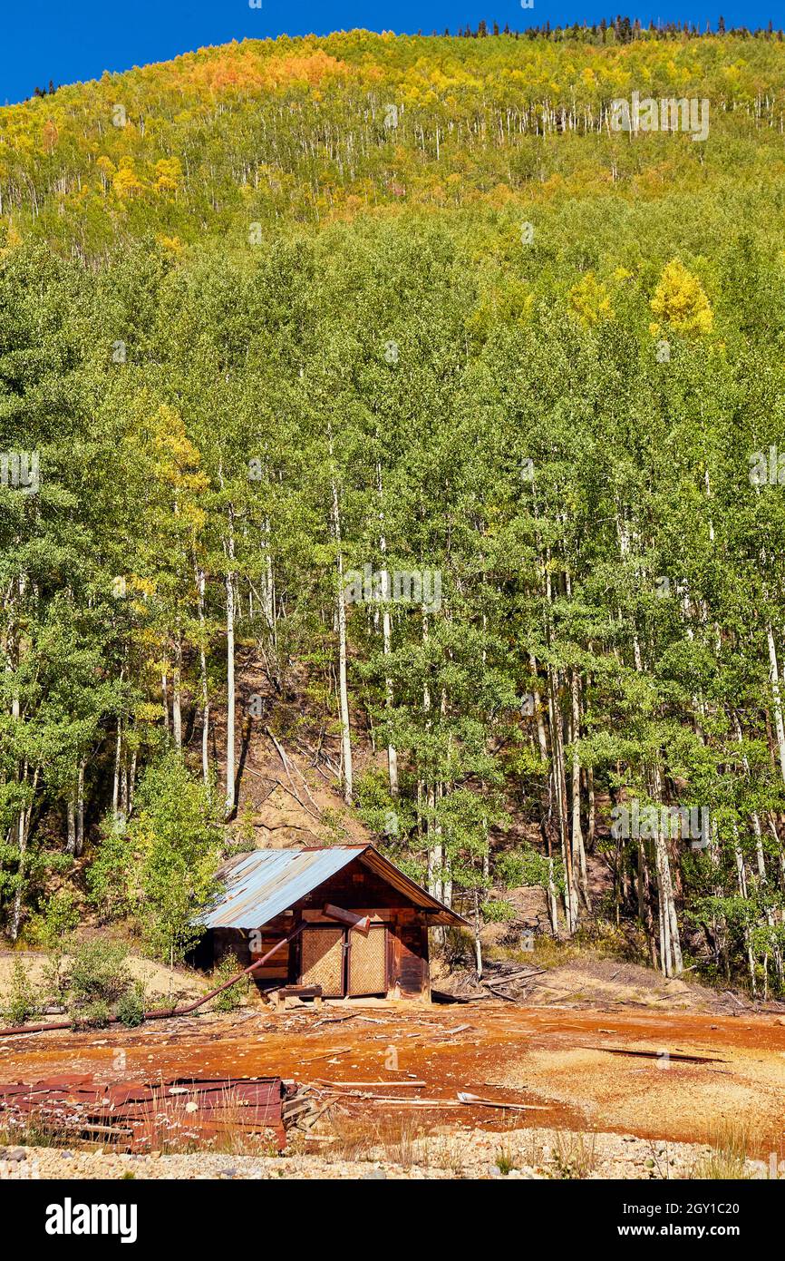 Small abandoned shack at base of large hill covered in green and yellow ...