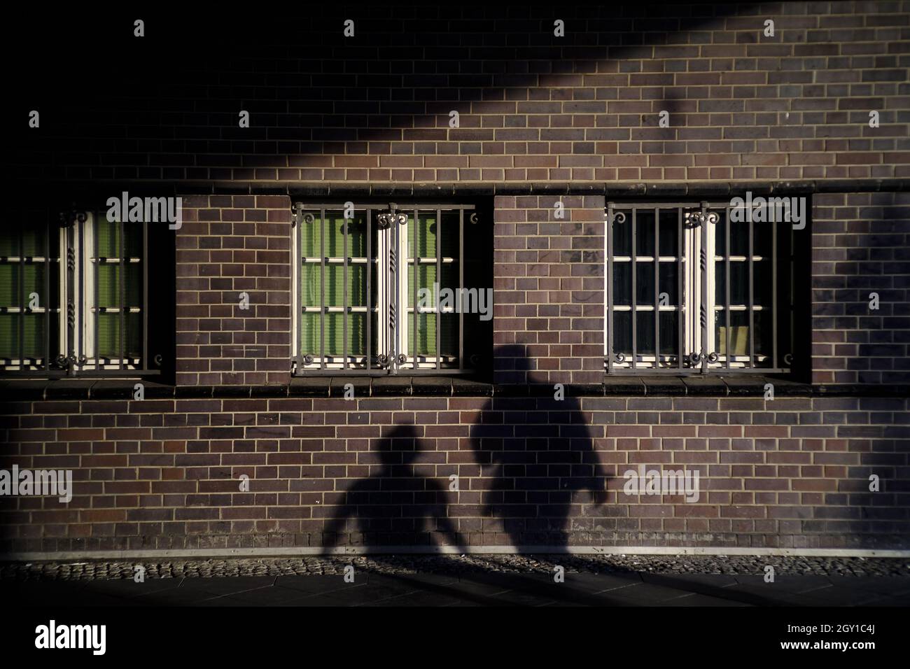 Shade of two people on the facade of the brick tiled building under the ...