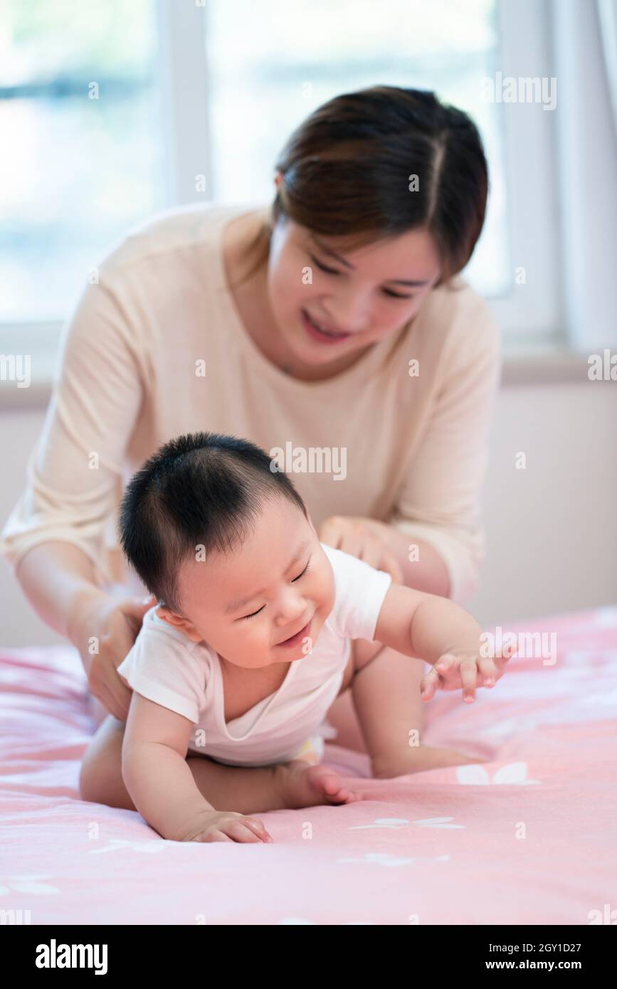 Young parents taking care of her baby on the bed Stock Photo - Alamy