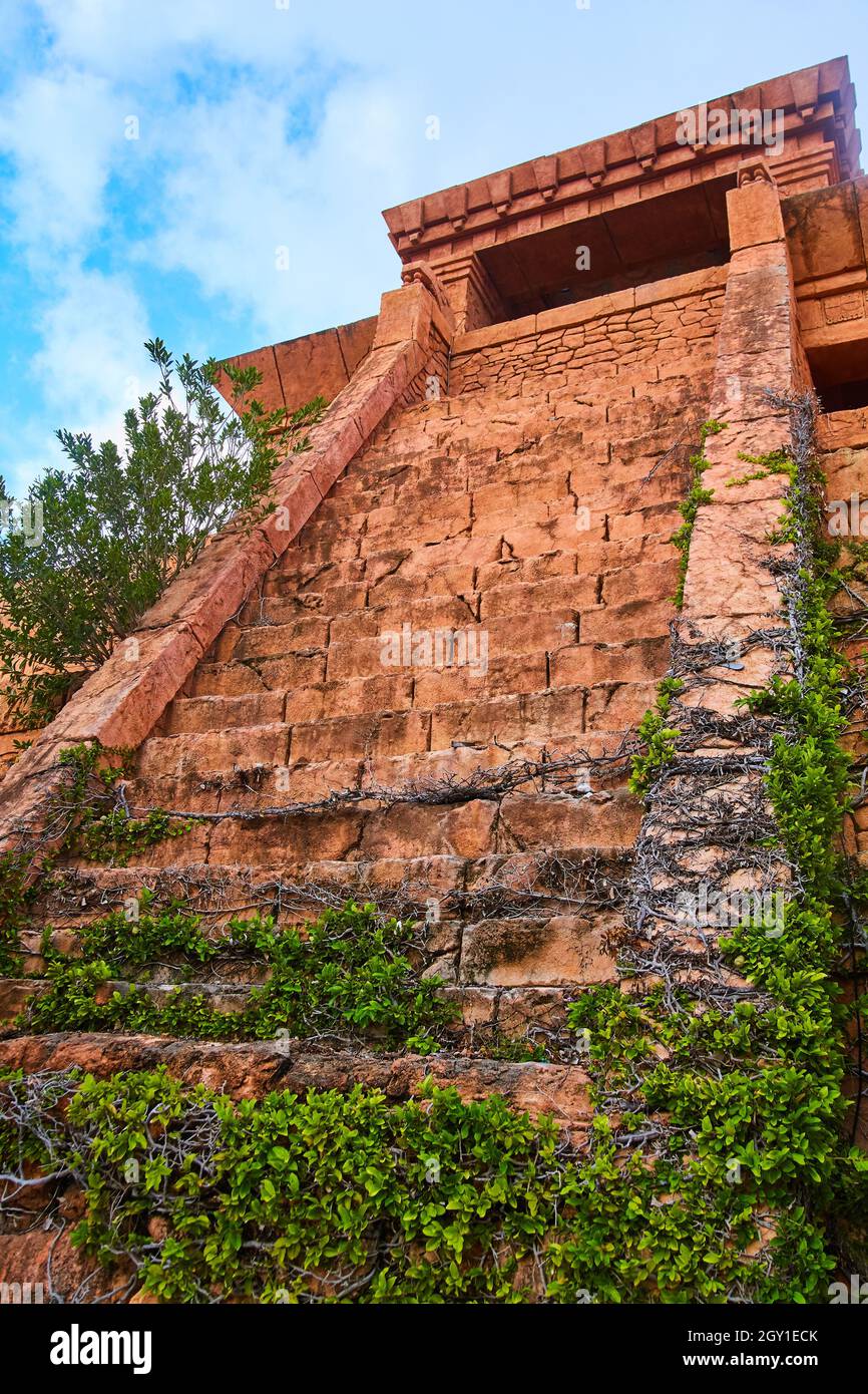 Mayan recreation with red stone steps covered in vines Stock Photo - Alamy