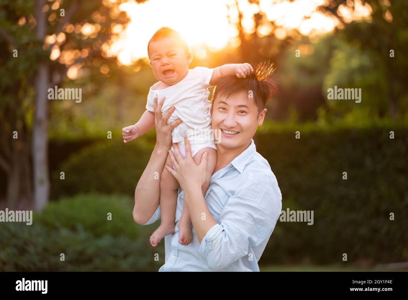 Young father raising his baby to play Stock Photo - Alamy