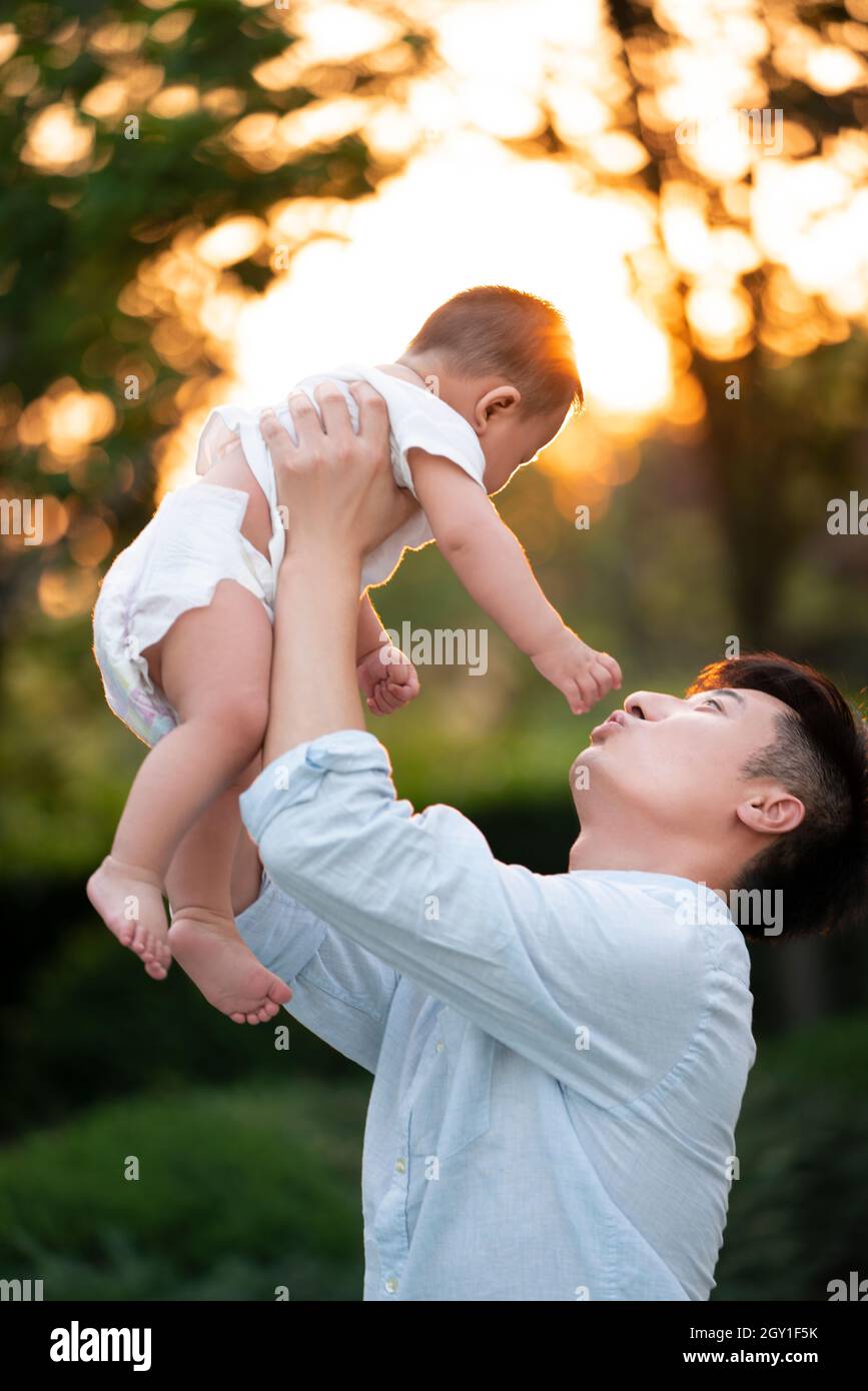 Young father raising his baby to play Stock Photo - Alamy