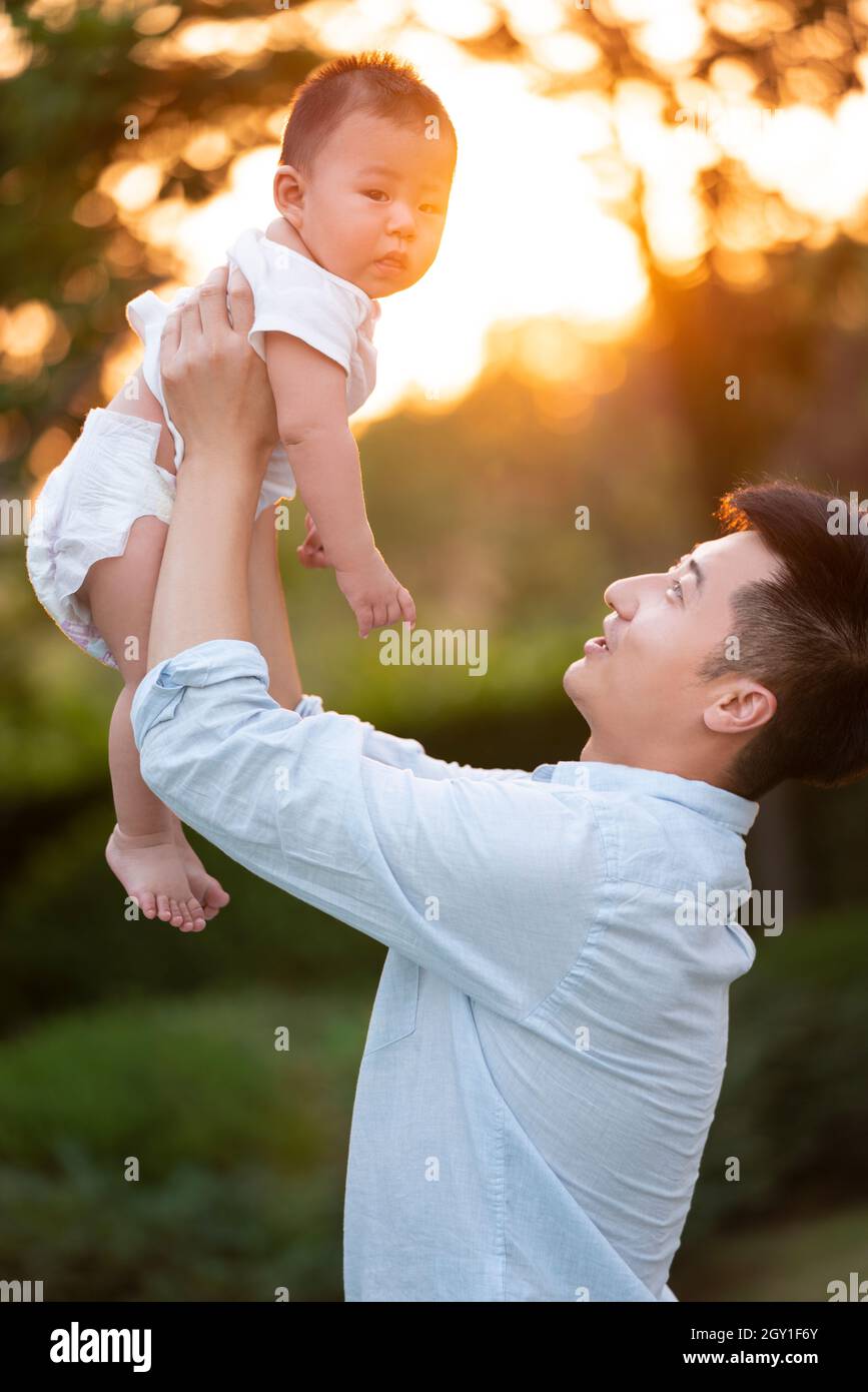 Young father raising his baby to play Stock Photo - Alamy