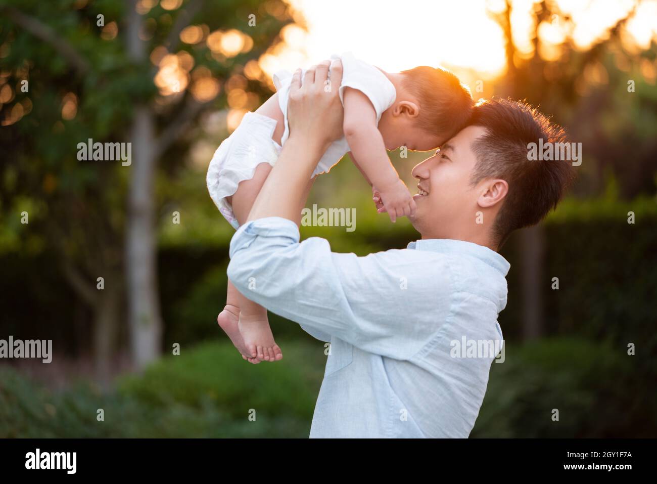 Young father raising his baby to play Stock Photo - Alamy