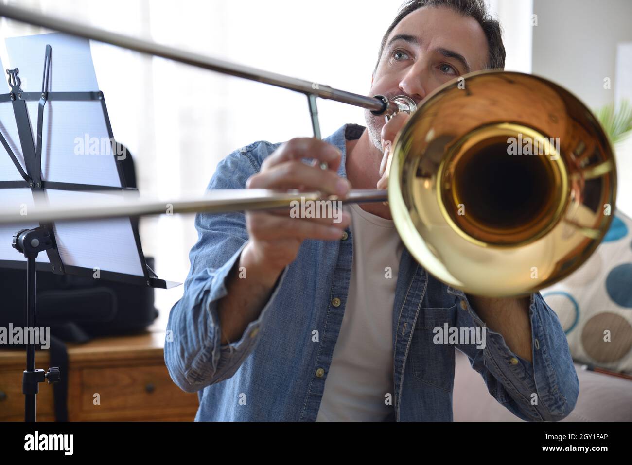Detail of trombonist practicing the trombone in living room at home ...
