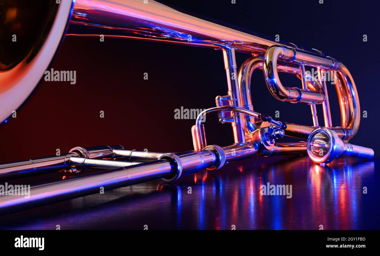 Jazz trombone illuminated with colored lights on black table. Front ...