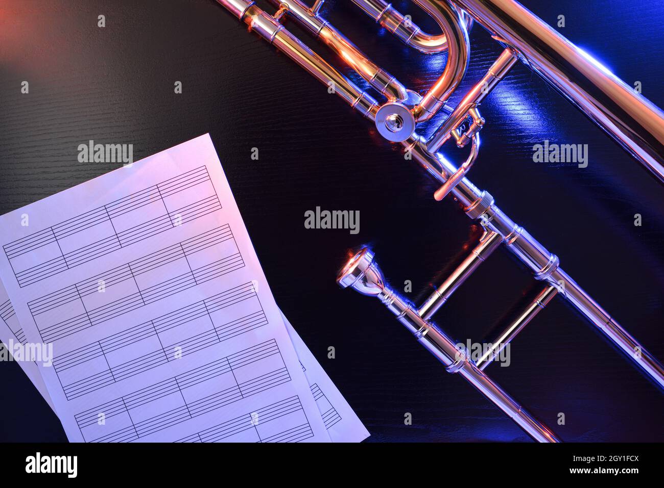 Jazz trombone with empty staff sheets illuminated with colored lights ...