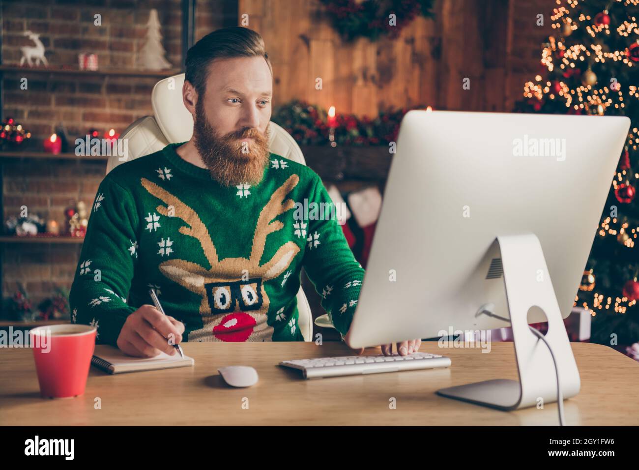 Photo of charming young serious focused man sit desk computer write ...