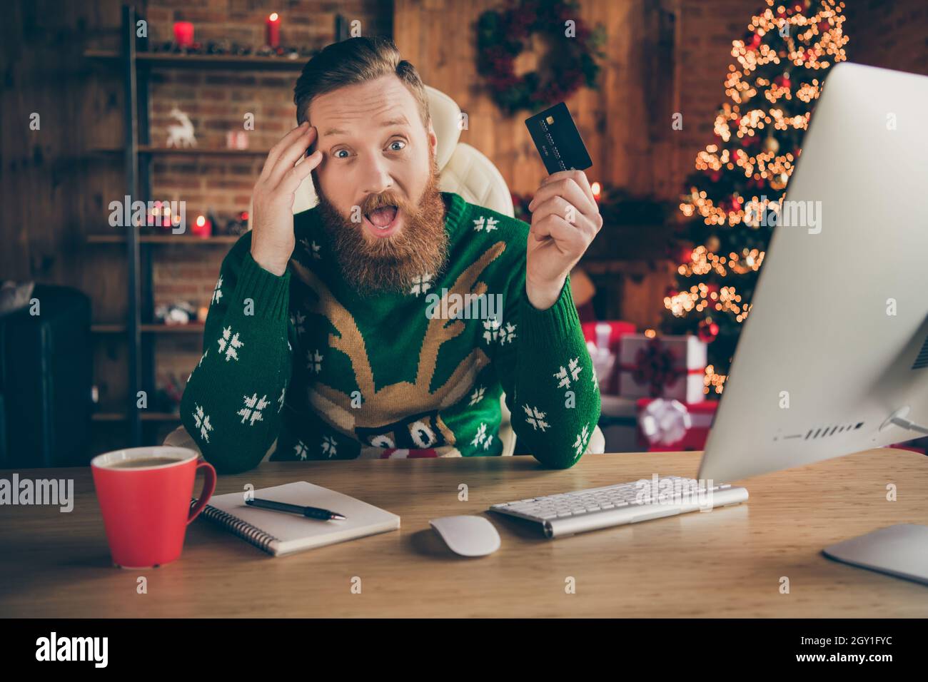 Photo of excited funky man sit desk hold debit card open mouth work pc ...