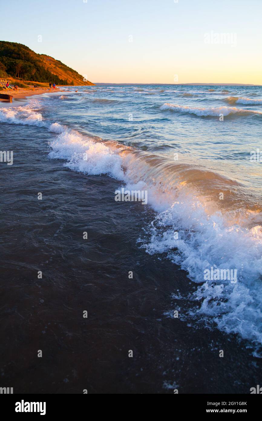 White crested waves roll towards the beach with a mountain and the ...