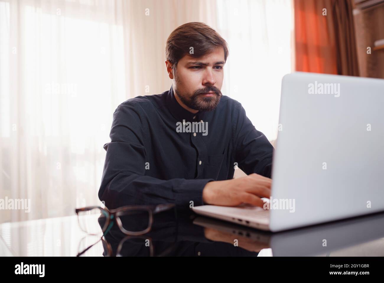 Handsome young man using laptop computer at home. Student men in his ...