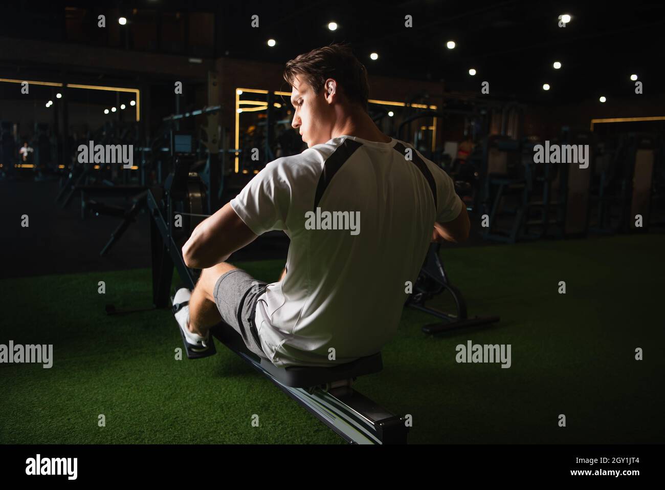 back view of man training on pull rope exercising machine in sitting ...