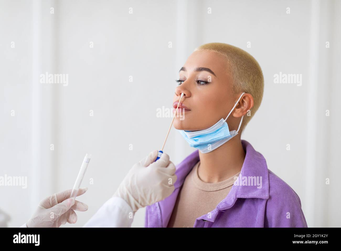 Doctor making covid-19 PCR test for female patient, free space. Young ...