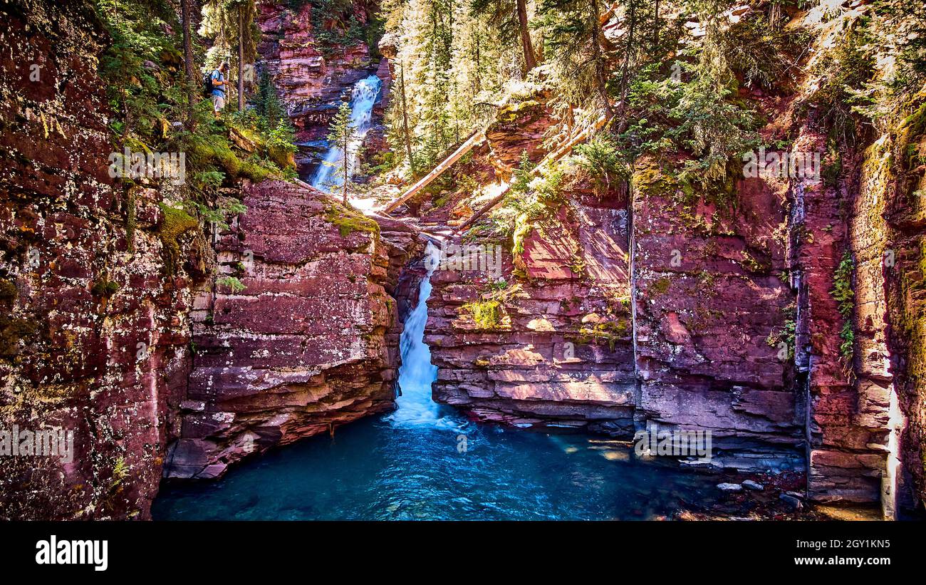 Deep gorge of lichen-covered red rocks with layers of waterfalls Stock ...