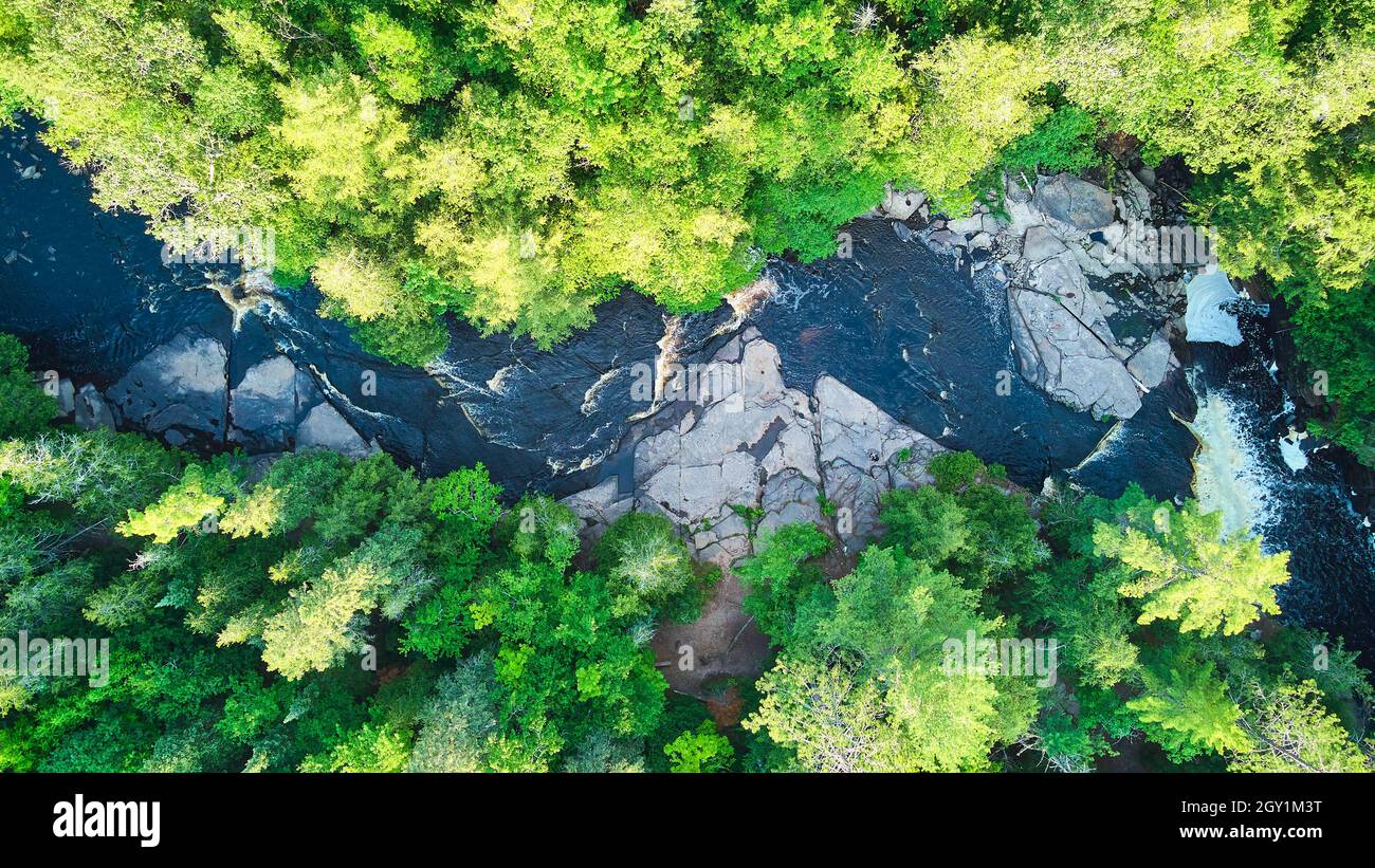 Aerial looking straight down over majestic river with cascades and lush ...
