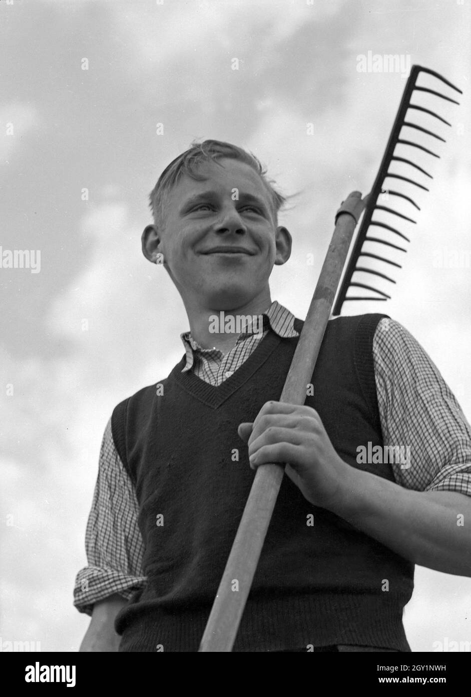 Zufriedener junger Landmann mit seinem Rechen, Deutschland 1930er Jahre ...