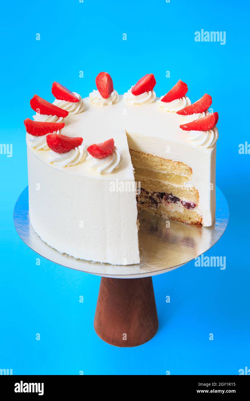 Sliced Birthday cake on the wooden cake stand. Beautiful white sponge ...