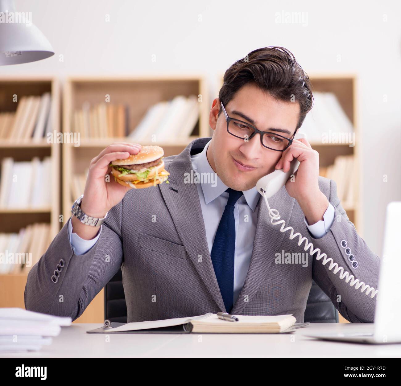 The hungry funny businessman eating junk food sandwich Stock Photo - Alamy