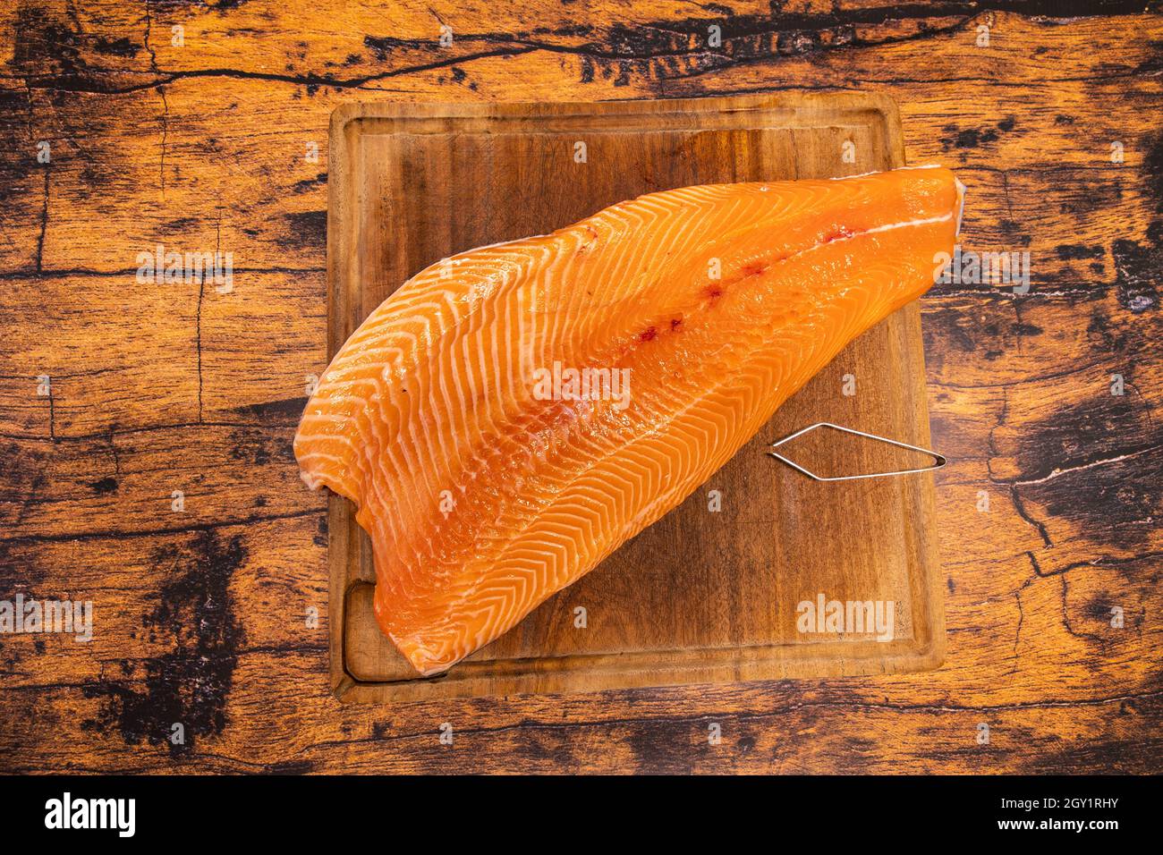 Large raw salmon fillet on a wooden board with fish bone pliers Stock ...