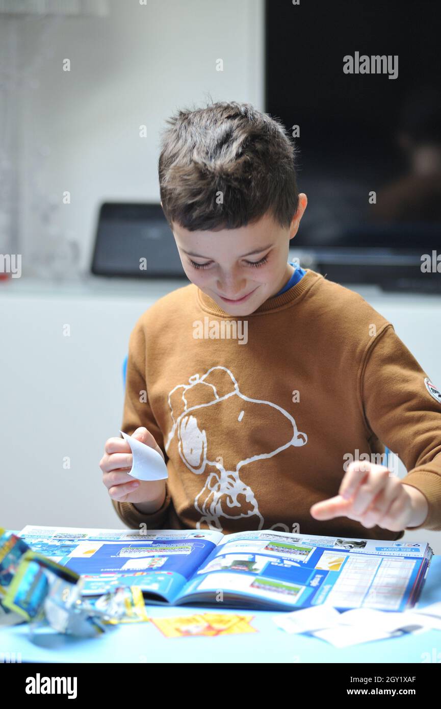Cute male child putting stickers in a book Stock Photo - Alamy