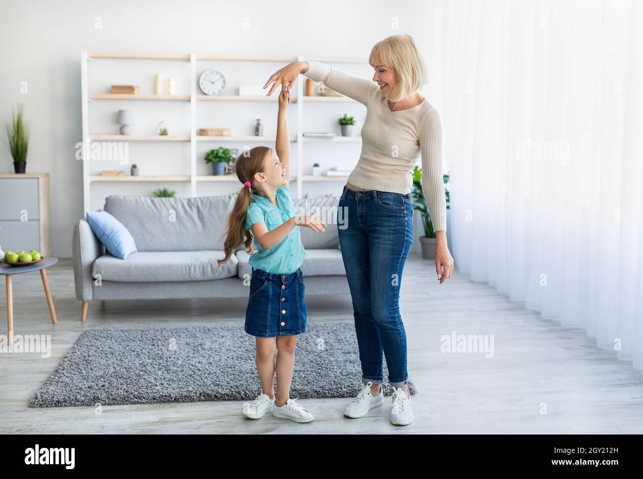 Cheerful grandmother dancing to music with little granddaughter Stock ...