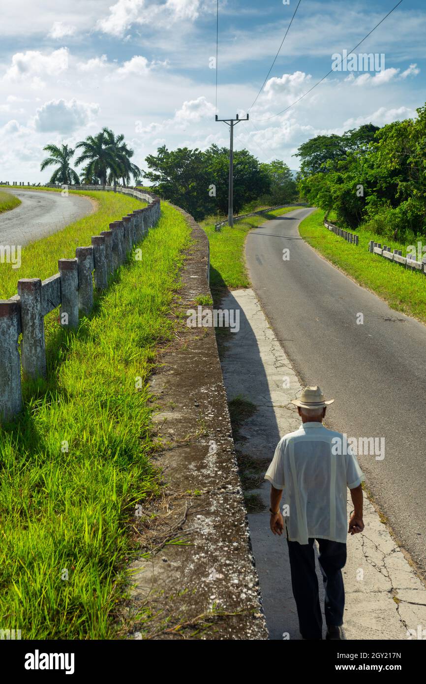 This is a man walking in a warm afternoon in a lonely road at the ...