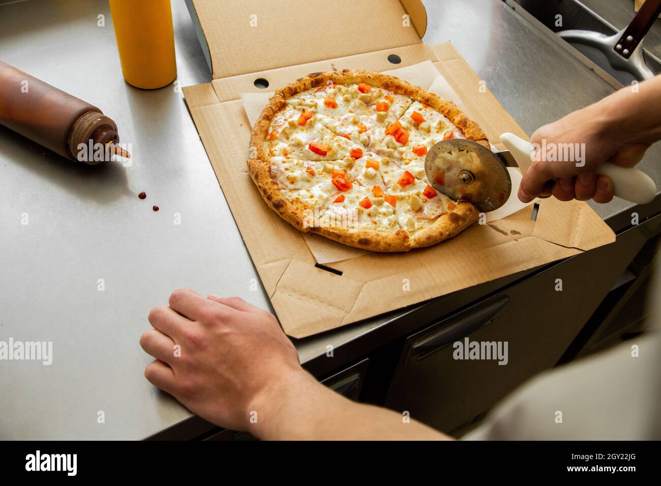 A pizzaiolo cuts a pizza with a round knife before wrapping it for ...
