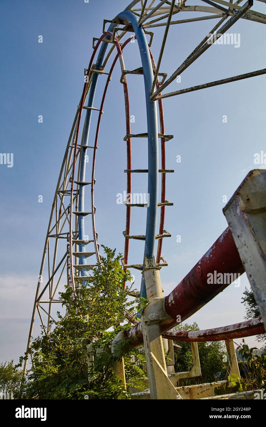 Worm's eye view of abandoned roller coaster in a broken down theme park ...