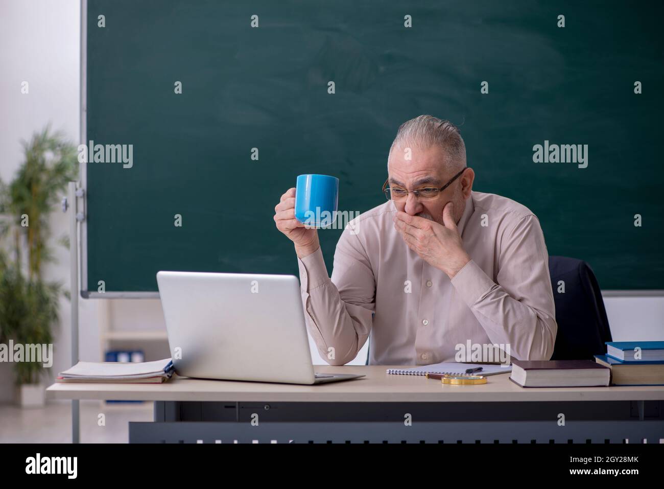 Old teacher drinking coffee in the classroom Stock Photo - Alamy